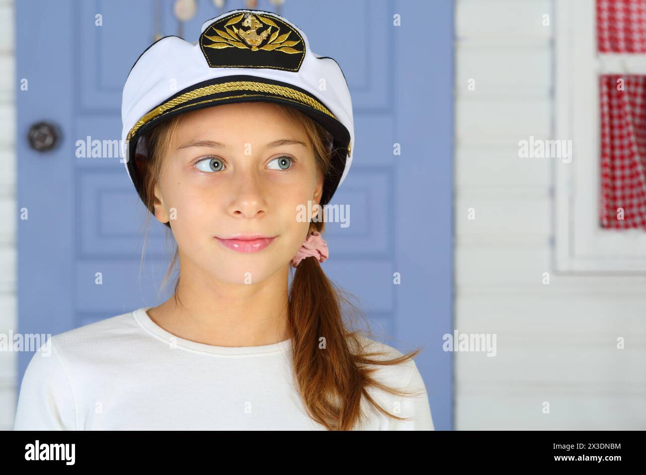 Portrait of teen girl in a white cap admiral in front of white house ...