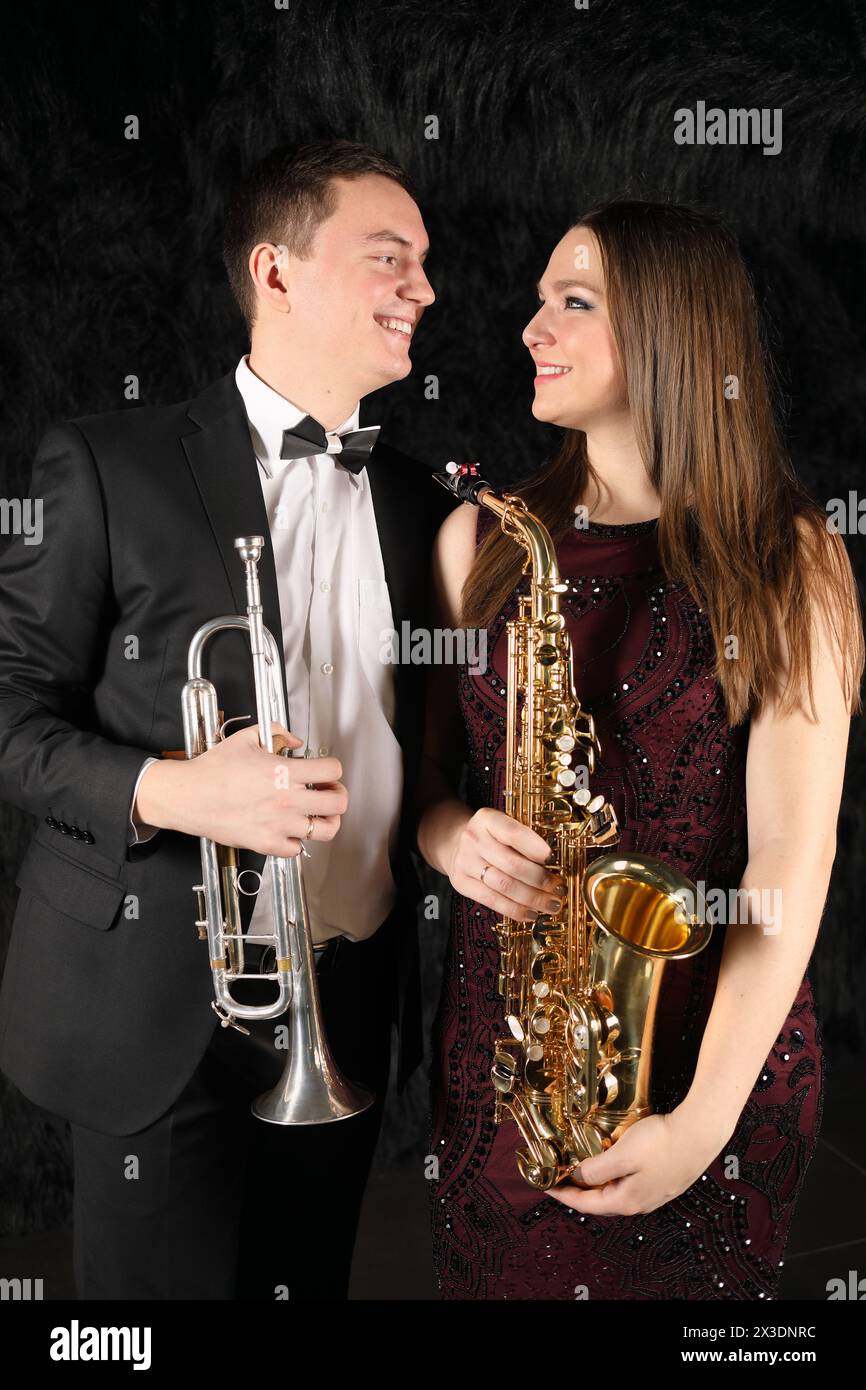 Happy musicians with wind instruments in their hands on a black fur ...