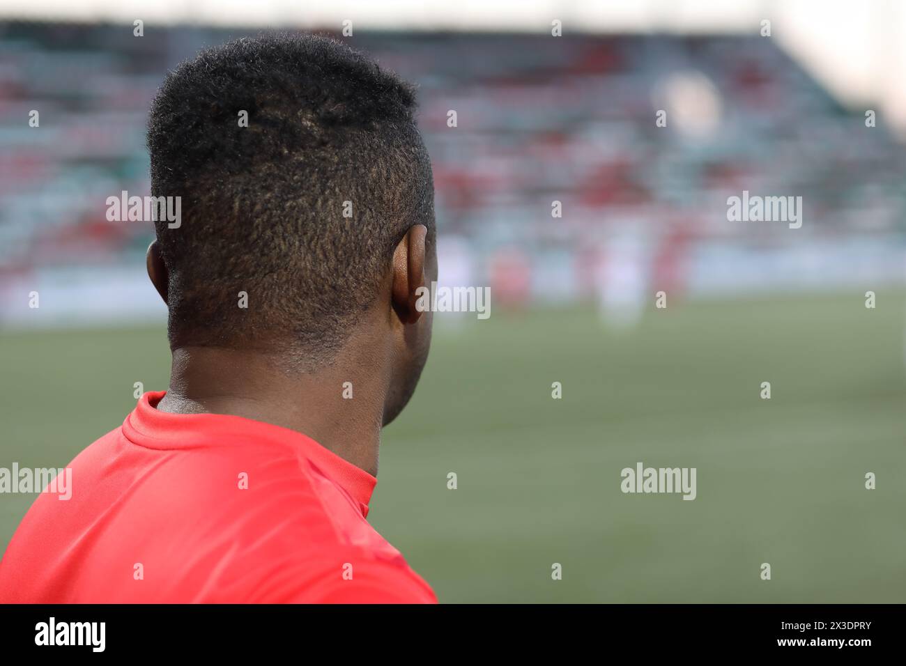 Black football player in a red T-shirt is looking at the football field ...
