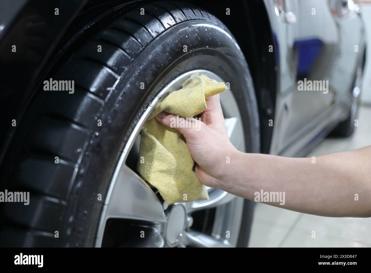 The washer of cars wipes a wheel of the car with a rag Stock Photo - Alamy