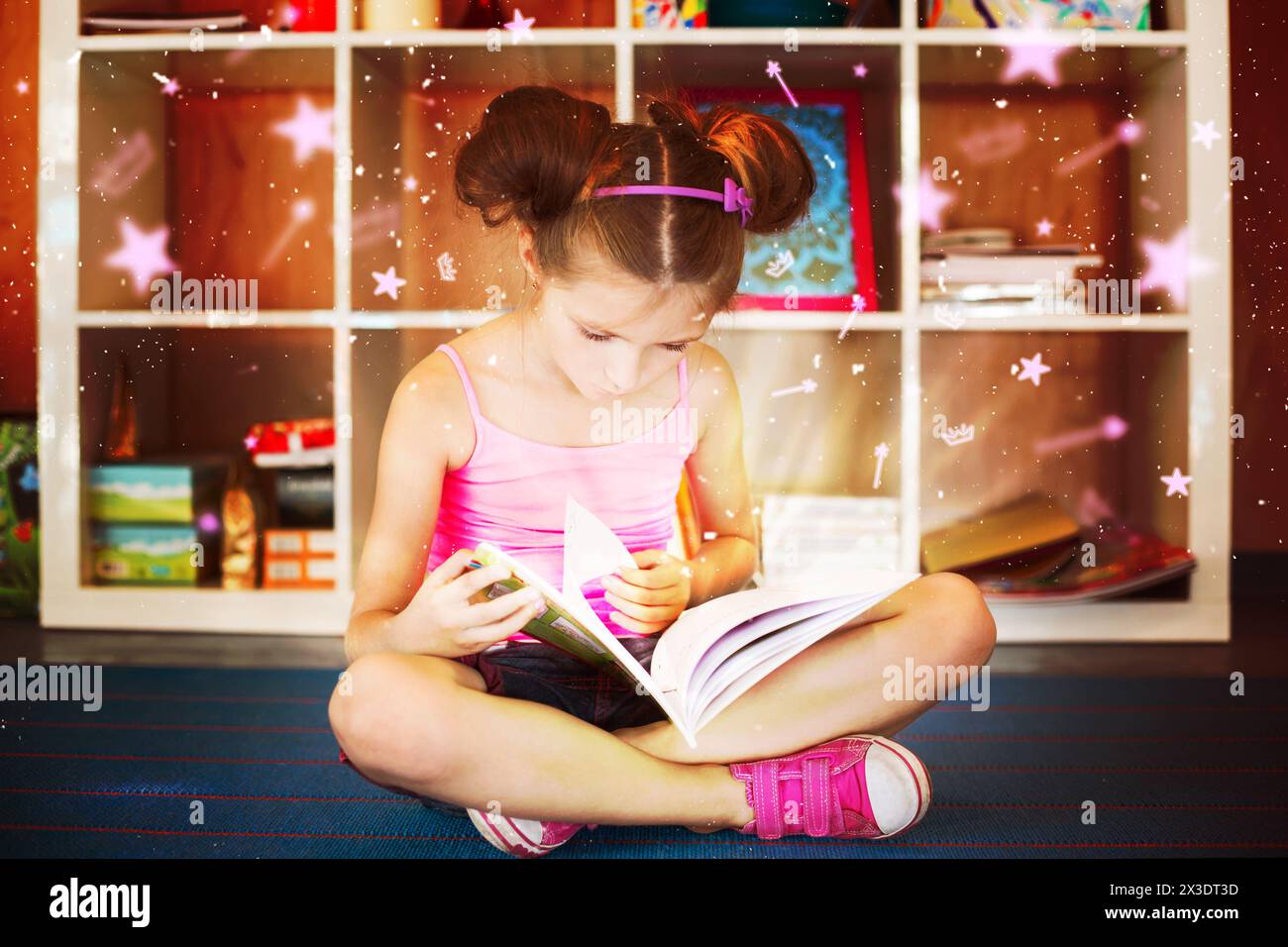 Little girl reads a magic book, stars, crowns and magic sticks fly ...