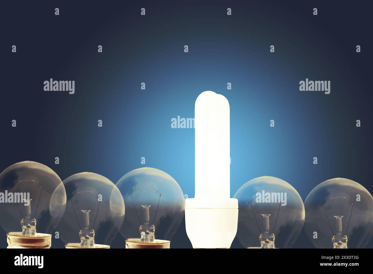Energy-saving light bulb lit among switched off incandescent lamps ...