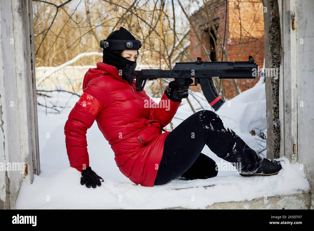 Woman in red jacket and ski mask aiming with gaming gun sitting on ...