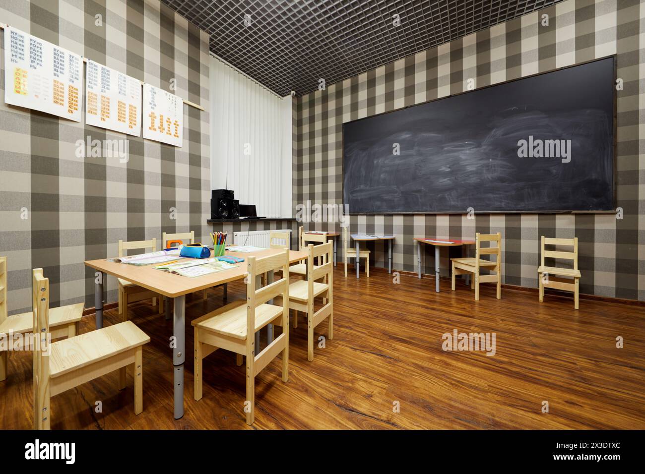 Interior of classroom with blackboard on wall and wooden furniture in ...