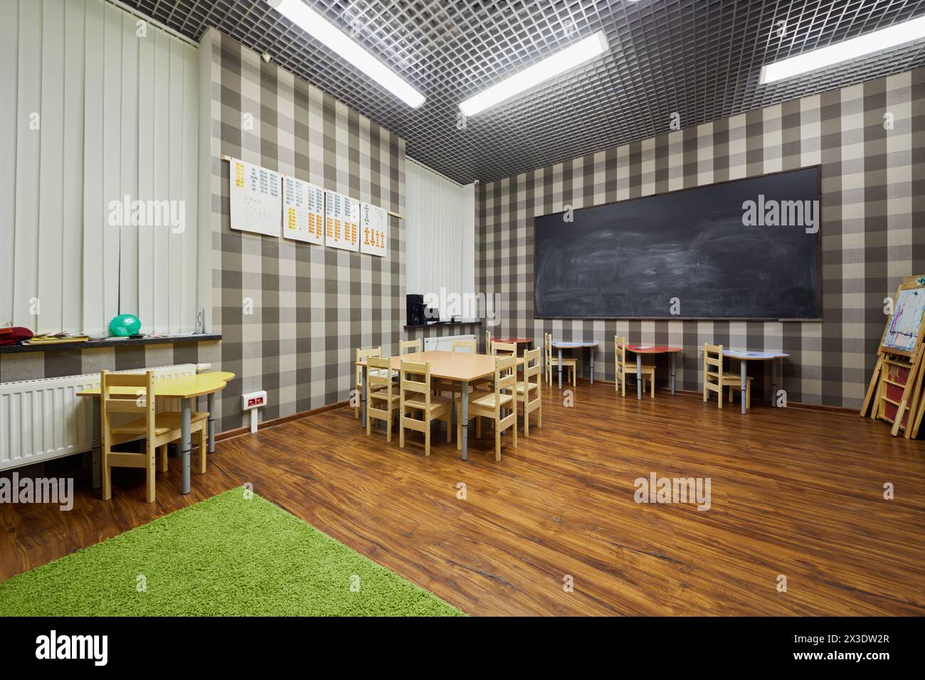 Interior of classroom with blackboard on wall and wooden furniture and ...