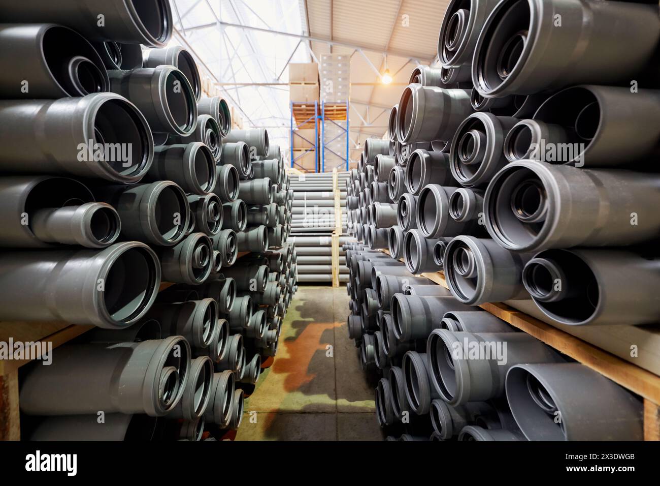 Packages of plastic pipes and cardboard boxes on shelves in factory ...