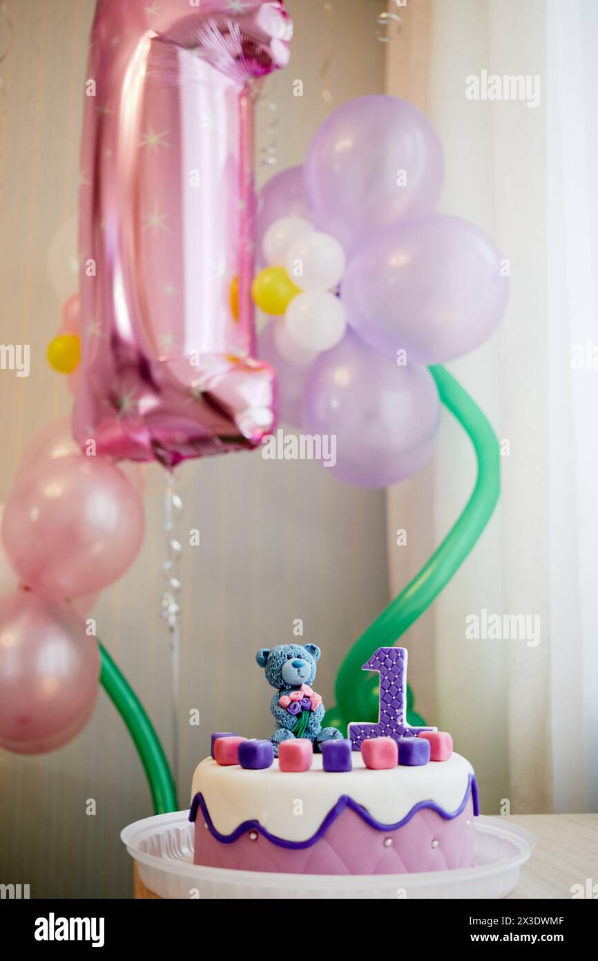 Birthday cake decorated with bear and number one on plate, balloons at ...