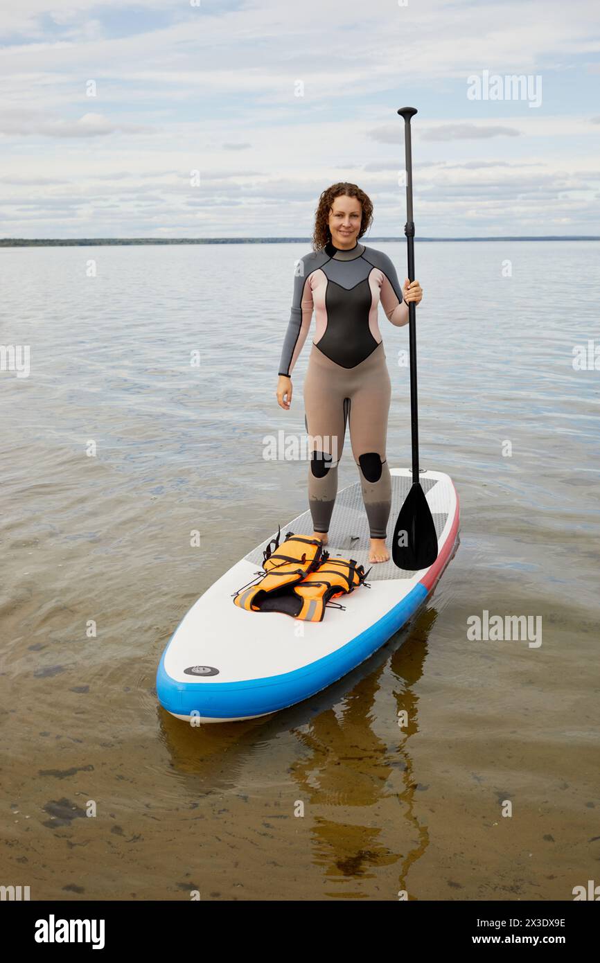 Woman in suit stands with paddle in hand on inflatable SUP board Stock ...