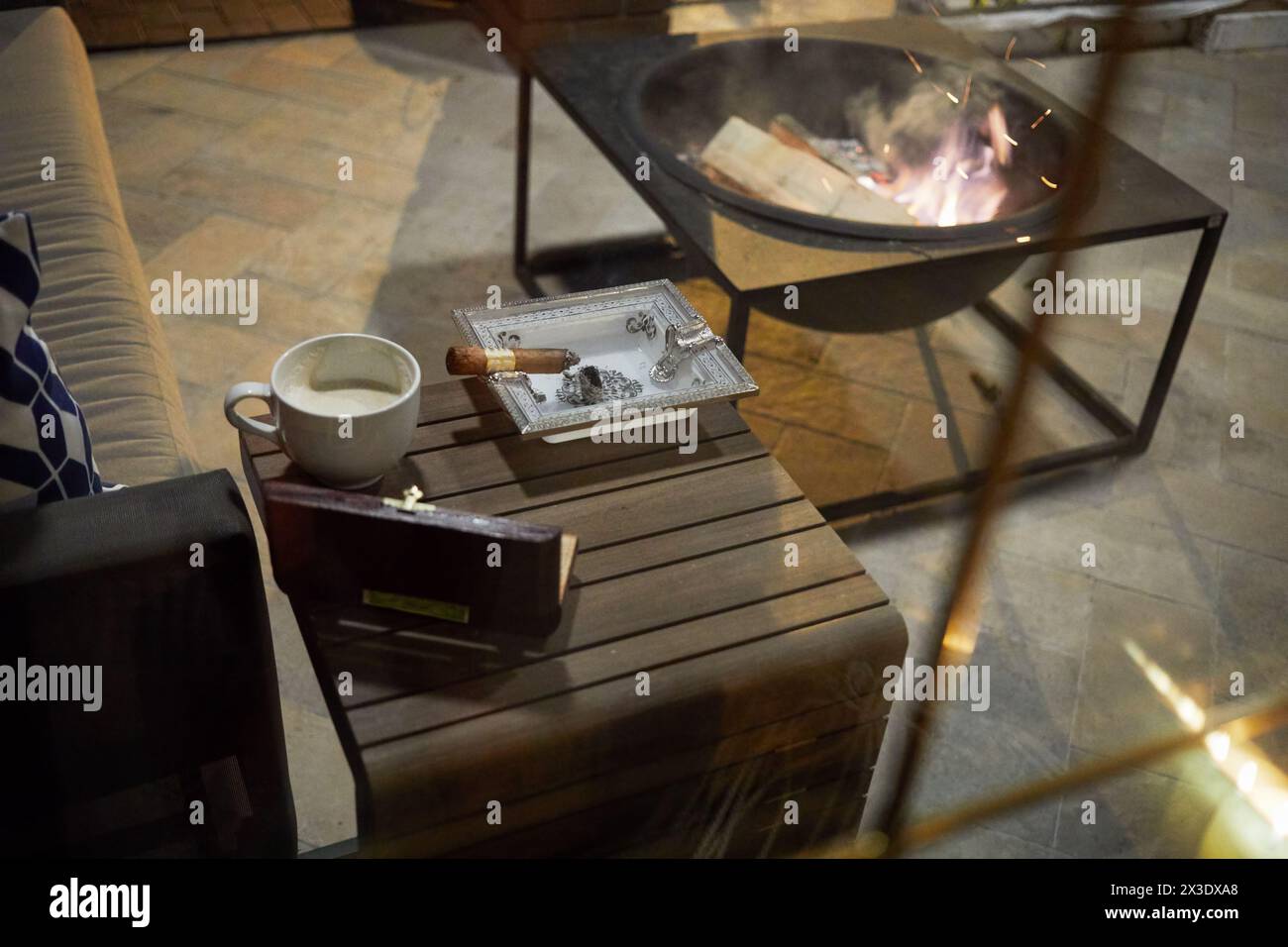 Small wooden cigar table with humidor, ashtray with burning cigar, cup ...