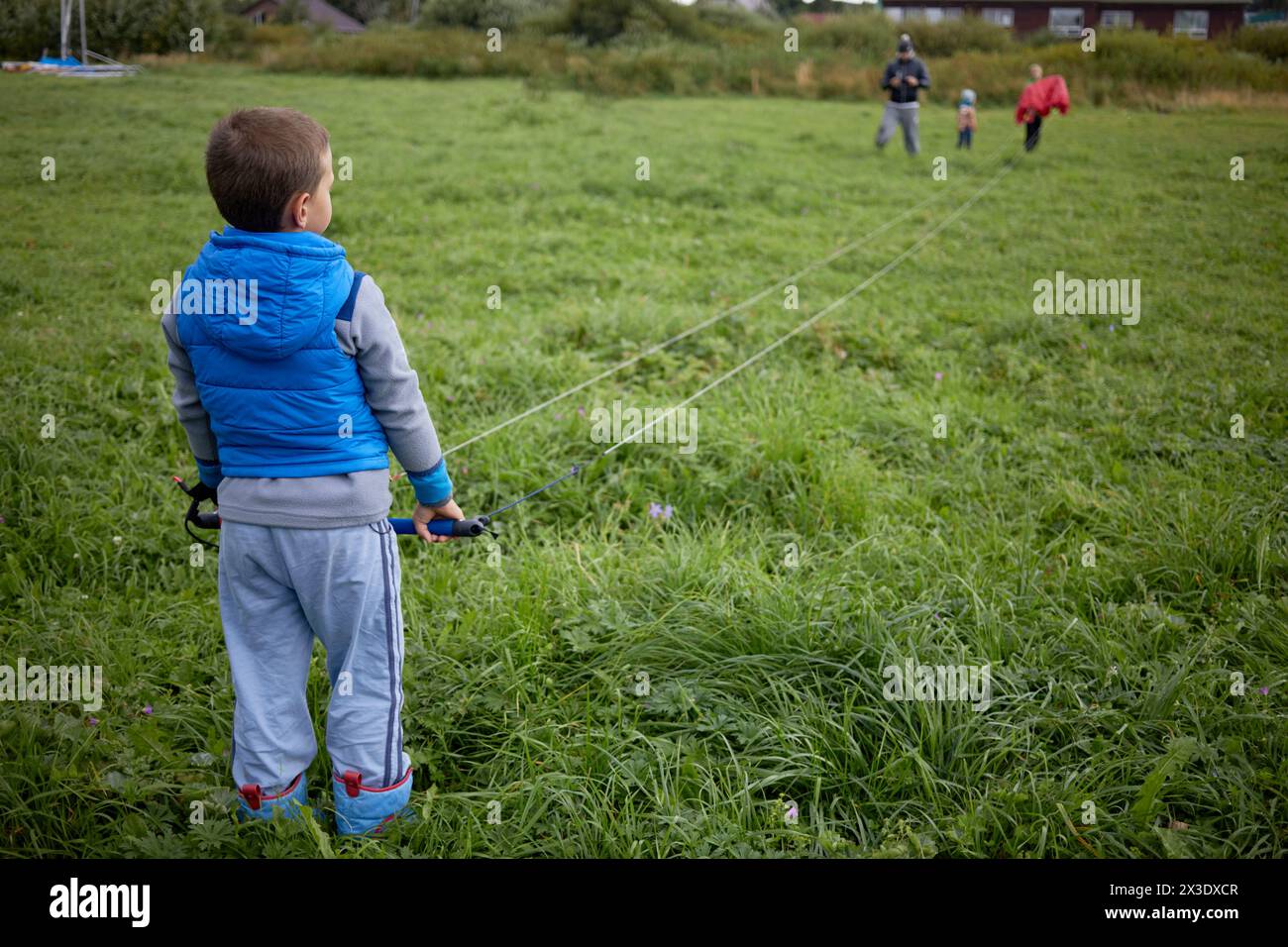 Boy stands holding control bar with attached flying lines of power kite ...