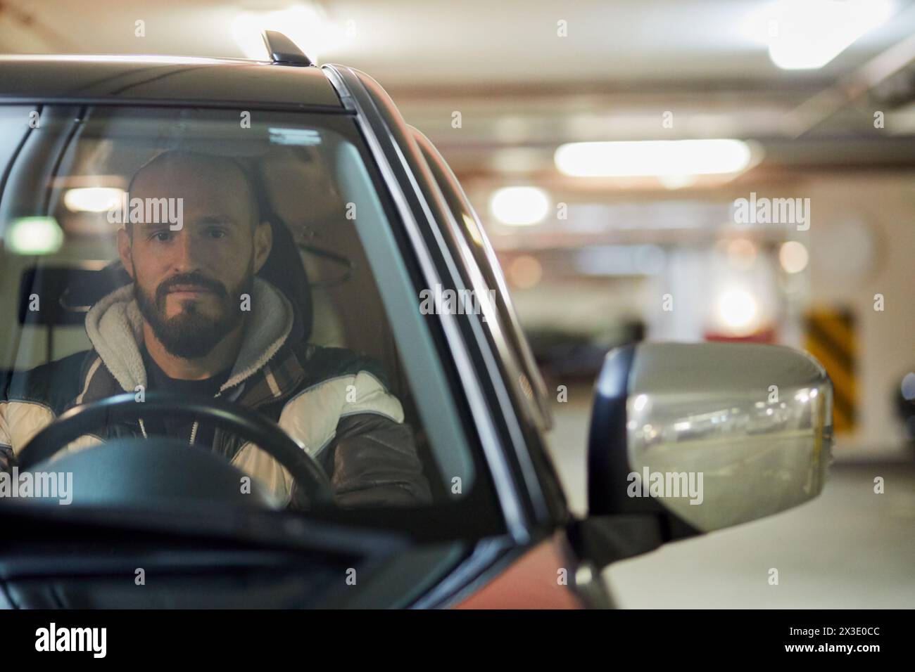 Bearded man sits on driver seat in car at underground parking Stock ...