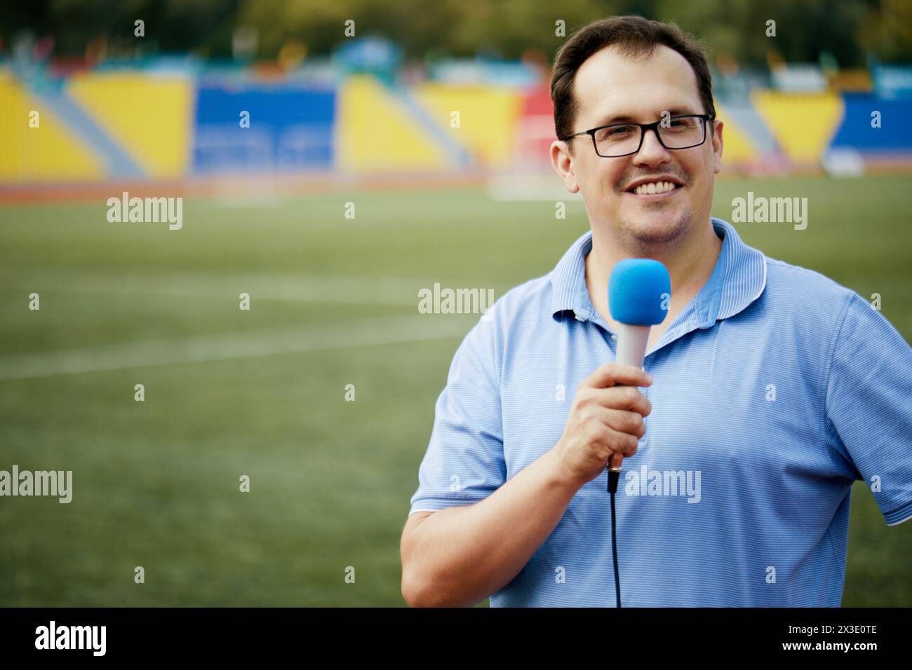 Smiling sportscaster with microphone is reporting from stadium Stock ...