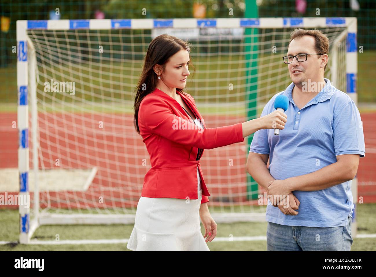Young woman journalist interviews man near goal at stadium Stock Photo - Alamy