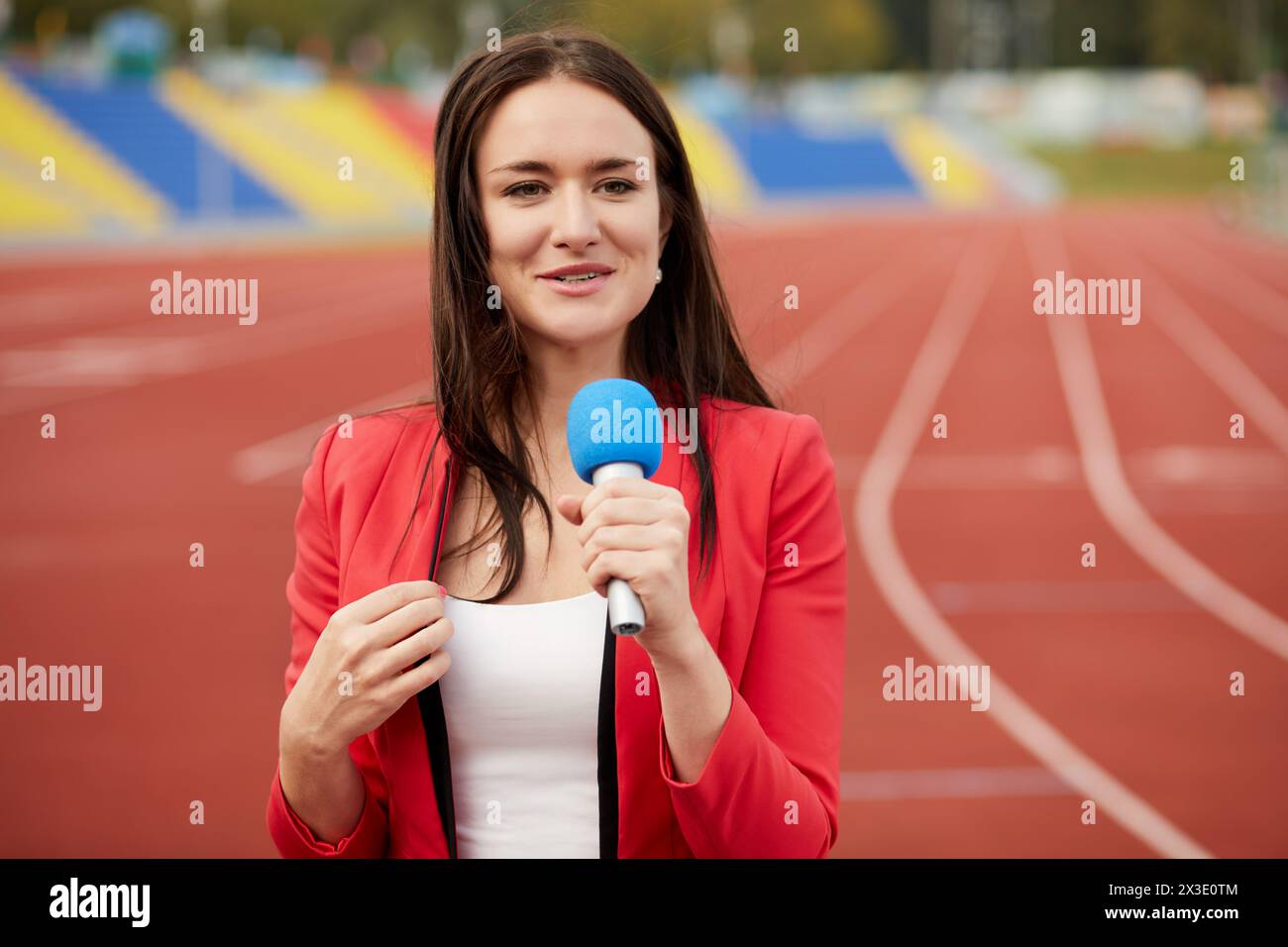 Young smiling woman journalist speaks into microphone at stadium Stock ...