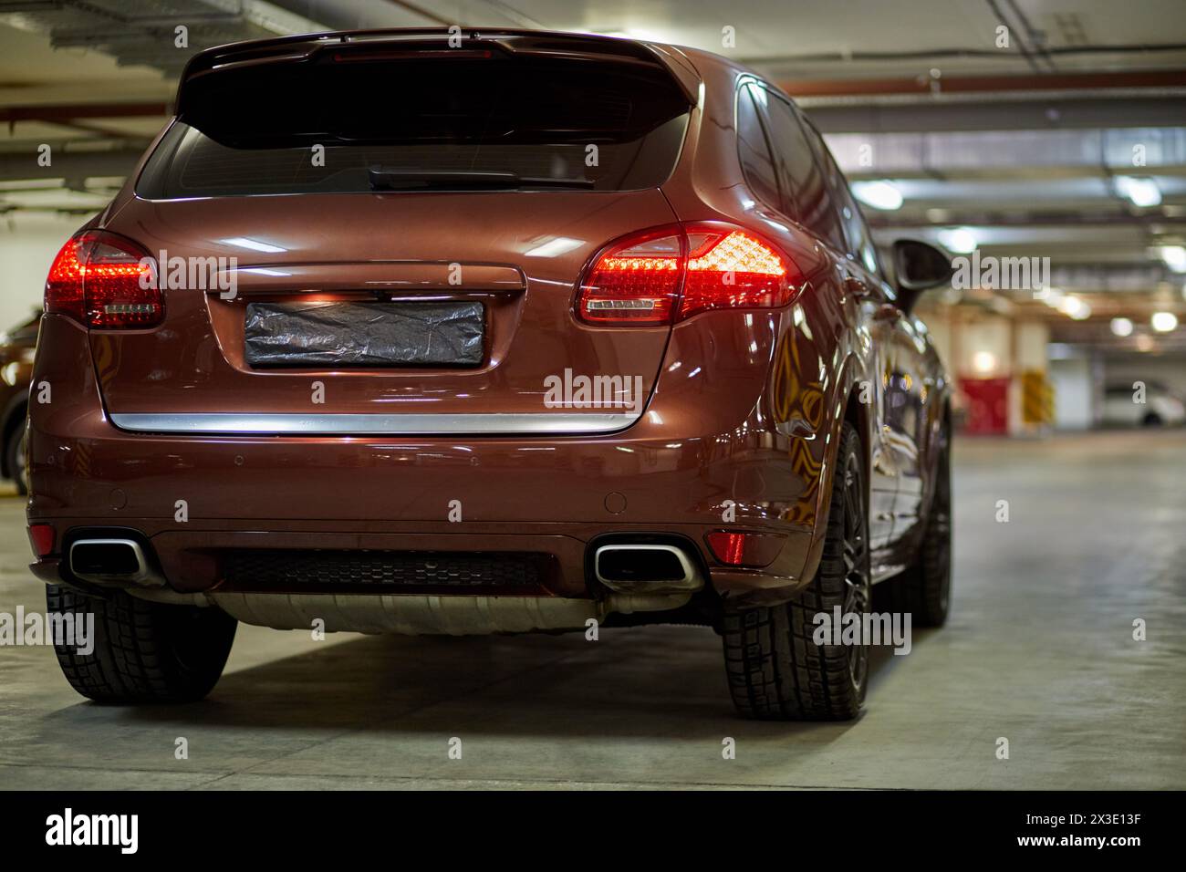 New modern car with tail lights on at underground parking, rear right ...