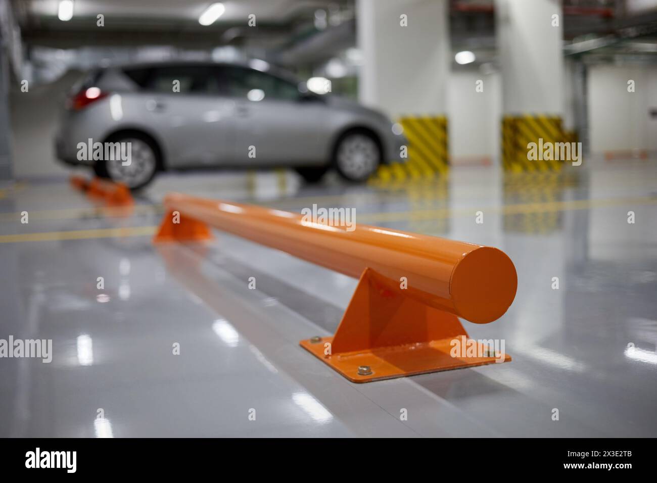 Mounted orange metal wheel stopper at underground parking, shallow dof ...