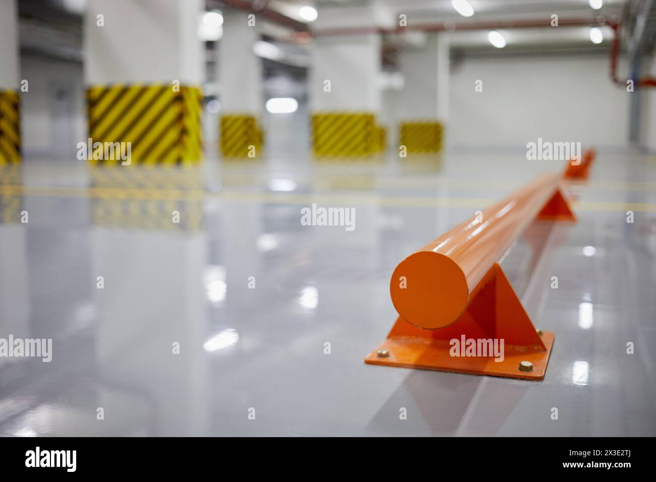 Mounted orange metal wheel stoppers at underground parking, focus on ...