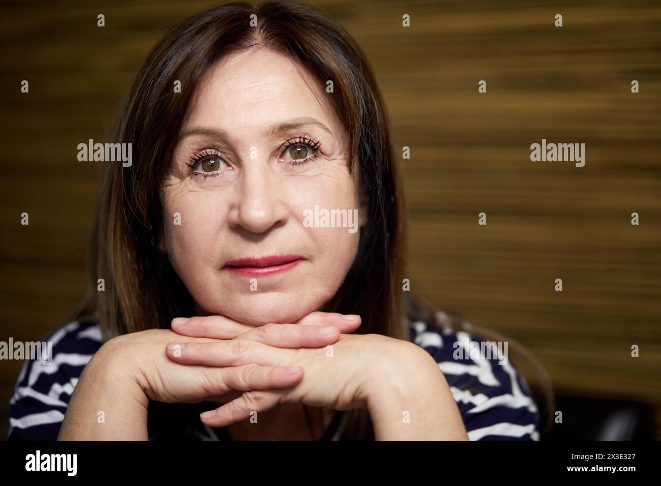 Close-up face of elderly woman sitting and propping chin with folded ...