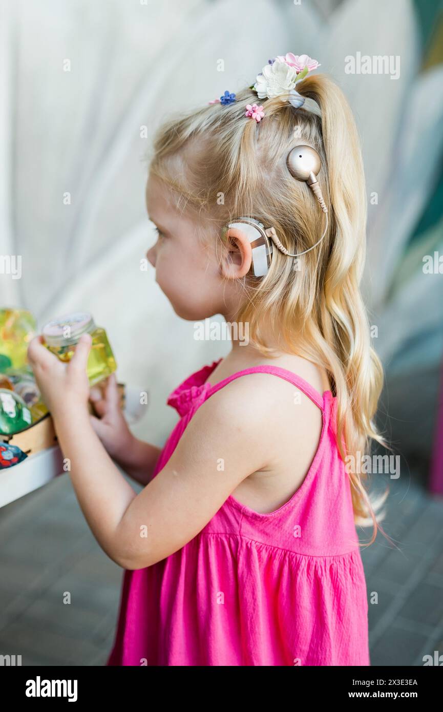 Child girl walks and have fun outdoor with cochlear implant on the head ...
