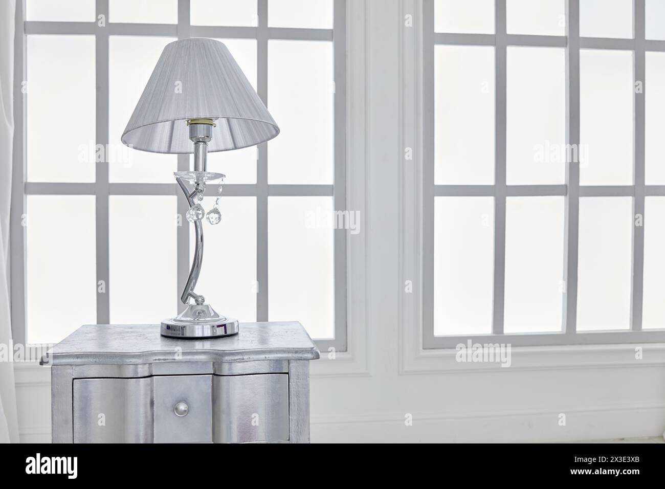 Table-lamp on bedside table against latticed window in room Stock Photo ...