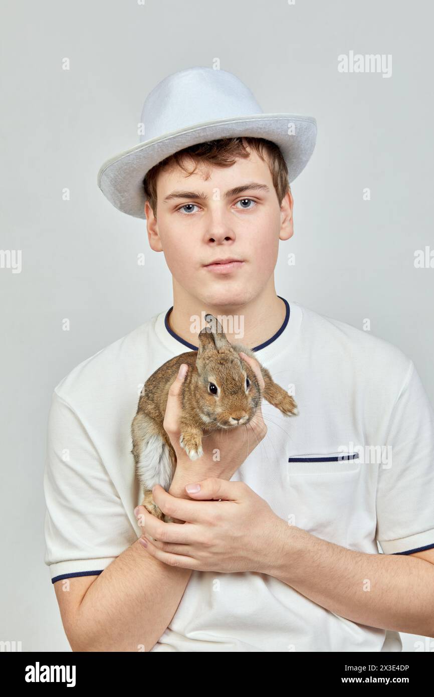 Half-length portrait of boy in hat holding rabbit in arms Stock Photo ...