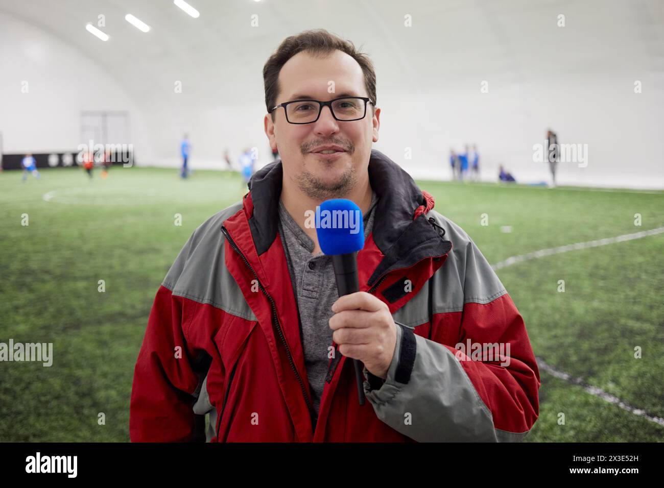 Smiling man with microphone reports from stadium Stock Photo - Alamy