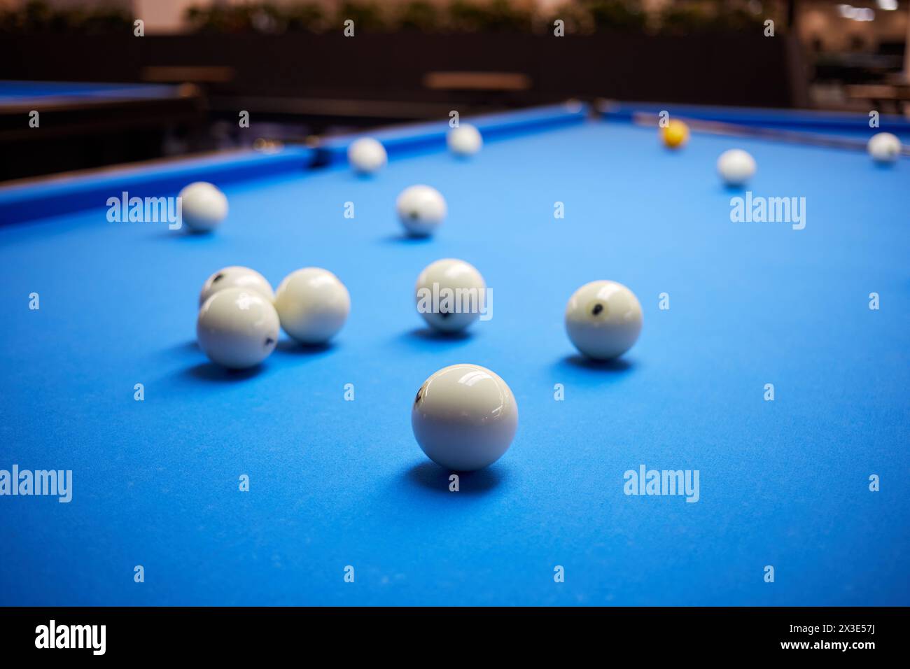 Disordered white balls and yellow cue ball on blue billiard table in ...