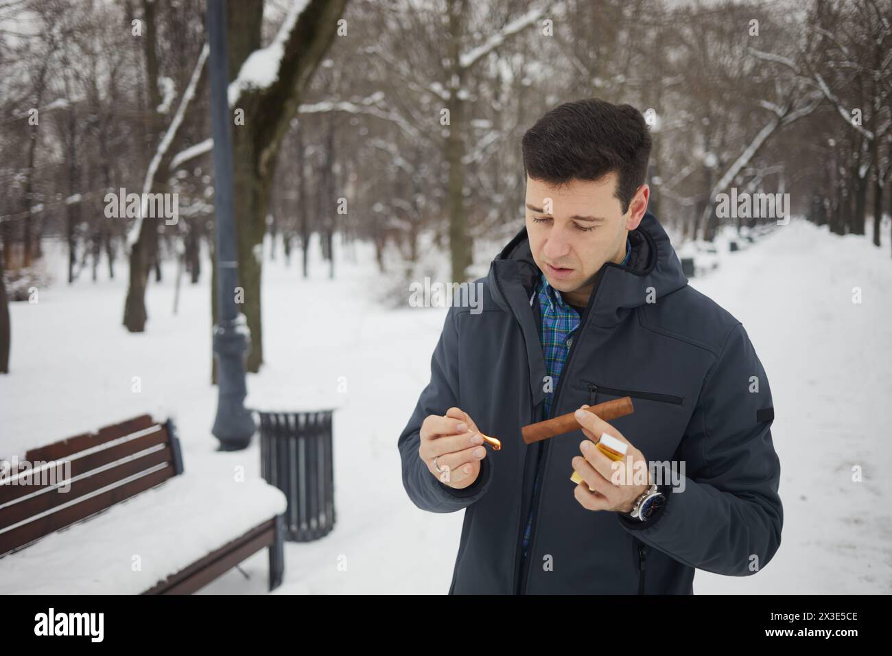 Man lighting cigar with burning match in winter park Stock Photo - Alamy