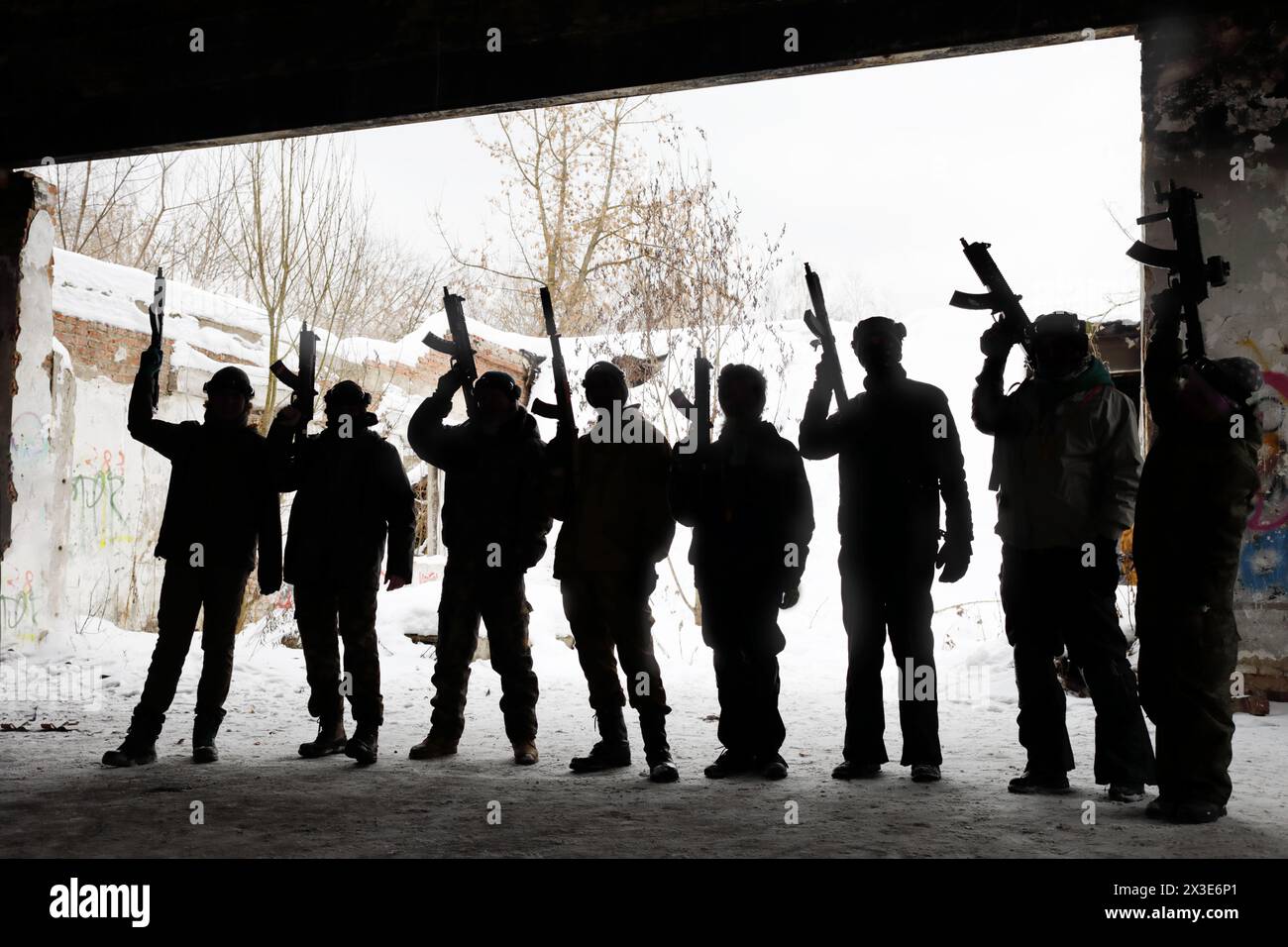 Eight unrecognizable young people with guns pose during lasertag game ...