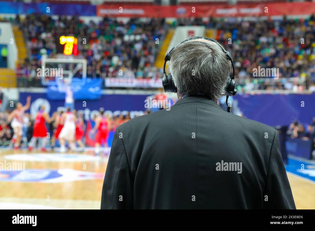 Commentator in headphones and suit at basketball game, back view Stock ...