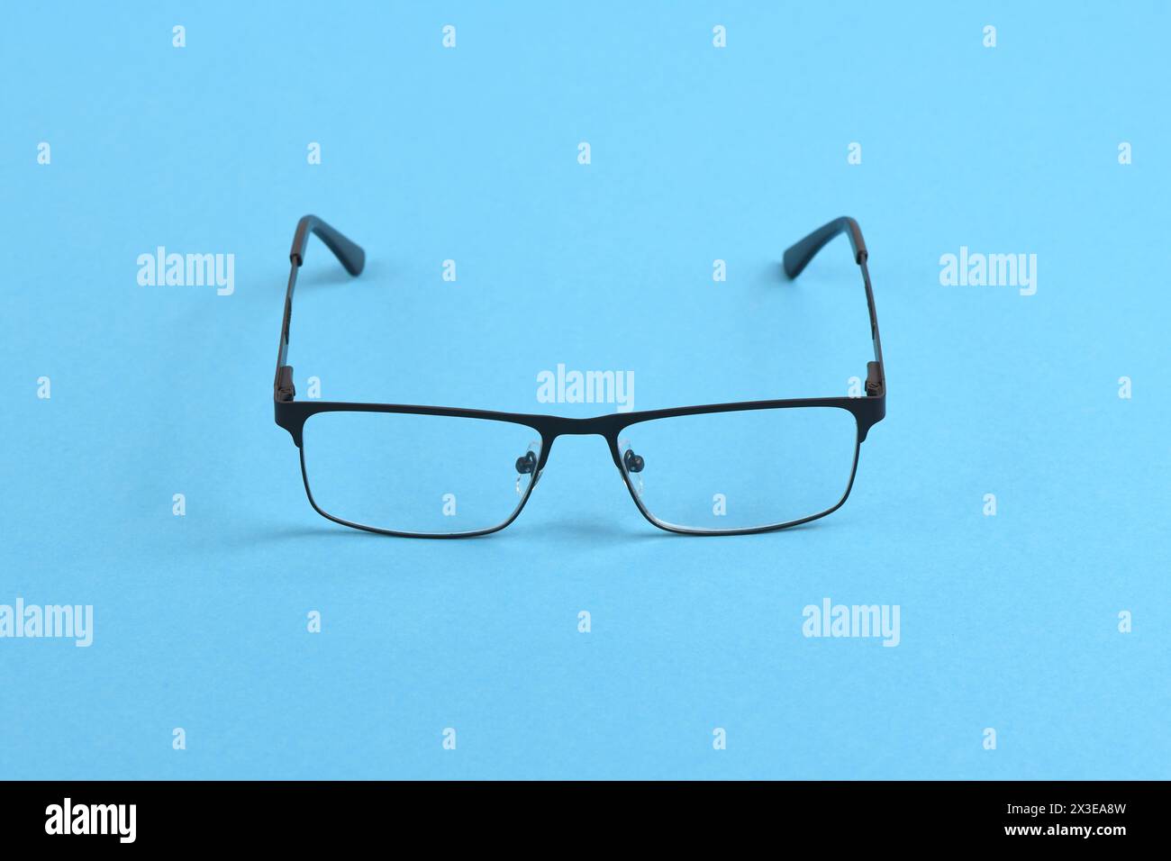 Hand holding plastic black glasses, isolated on blue background. High ...