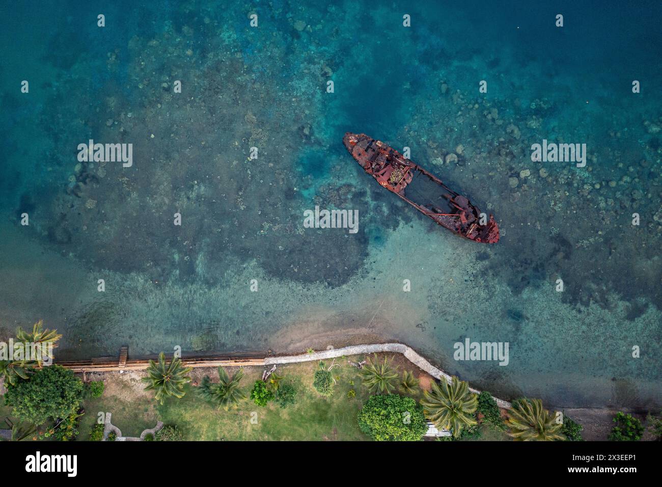 Top view of rusty wrecked boat in turquoise water near tropical shore ...