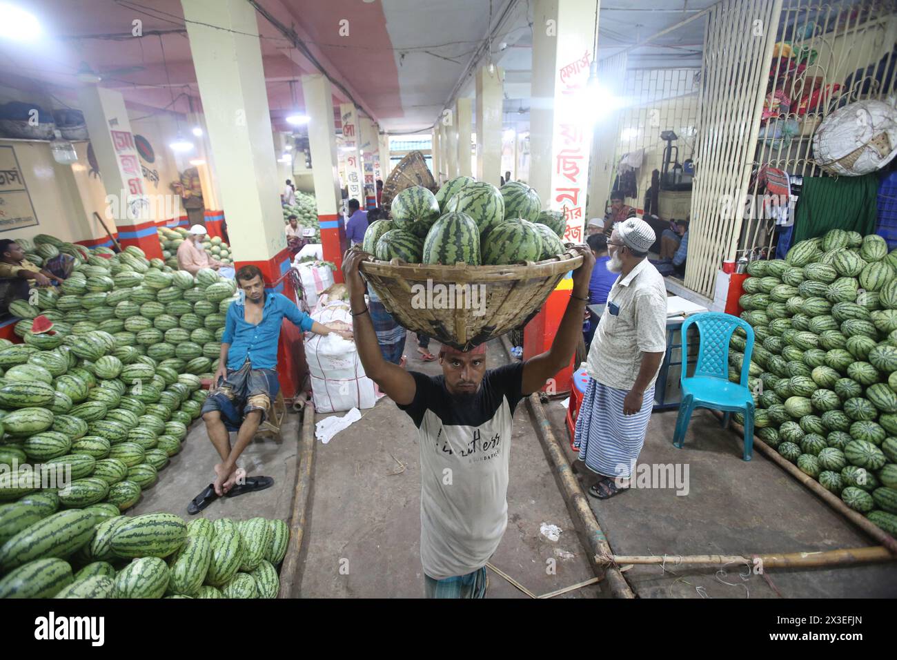 Dhaka. 26th Apr, 2024. A vendor carries watermelons at a wholesale ...