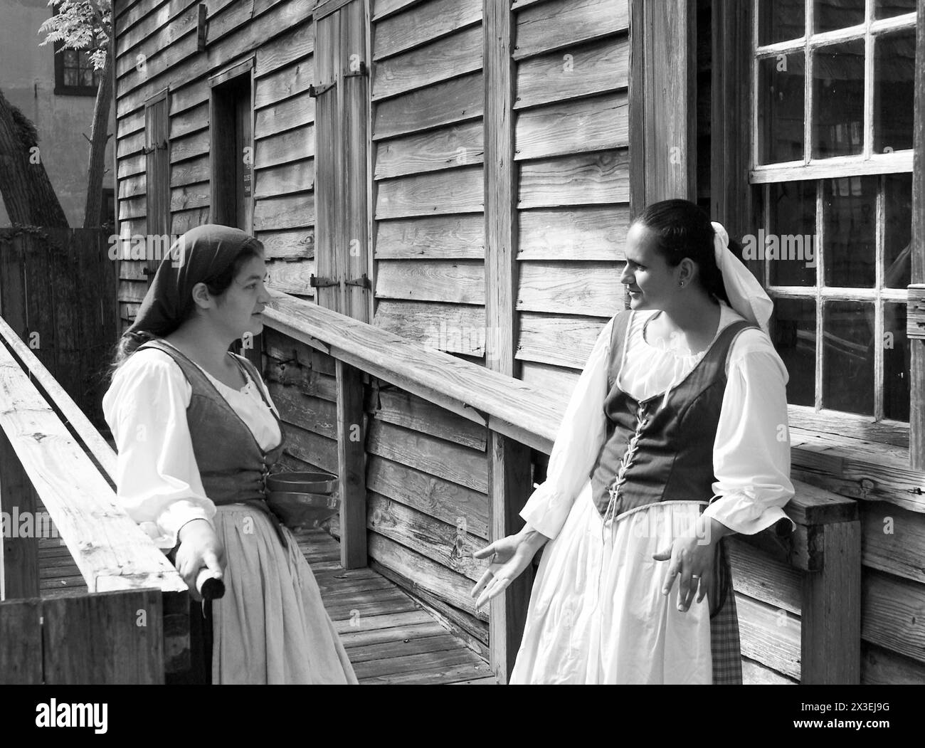 Two Hispanic women adorned in colonial attire engage in conversation ...