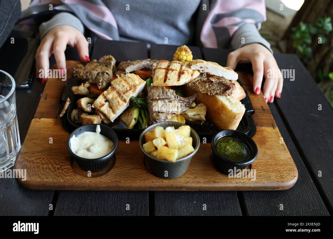 Mixed grill platter includes chicken, steak and veggies, beside two ...