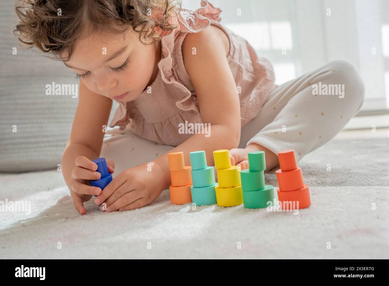 beautiful little girl has fun stacking blocks and pieces of sustainable ...