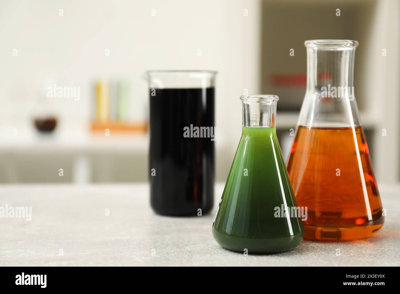 Flasks and beaker with different types of crude oil on light grey table ...