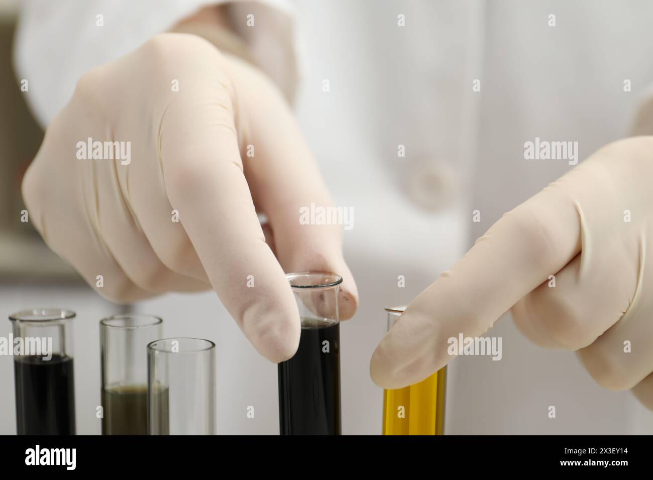 Laboratory worker holding test tubes with different types of crude oil ...