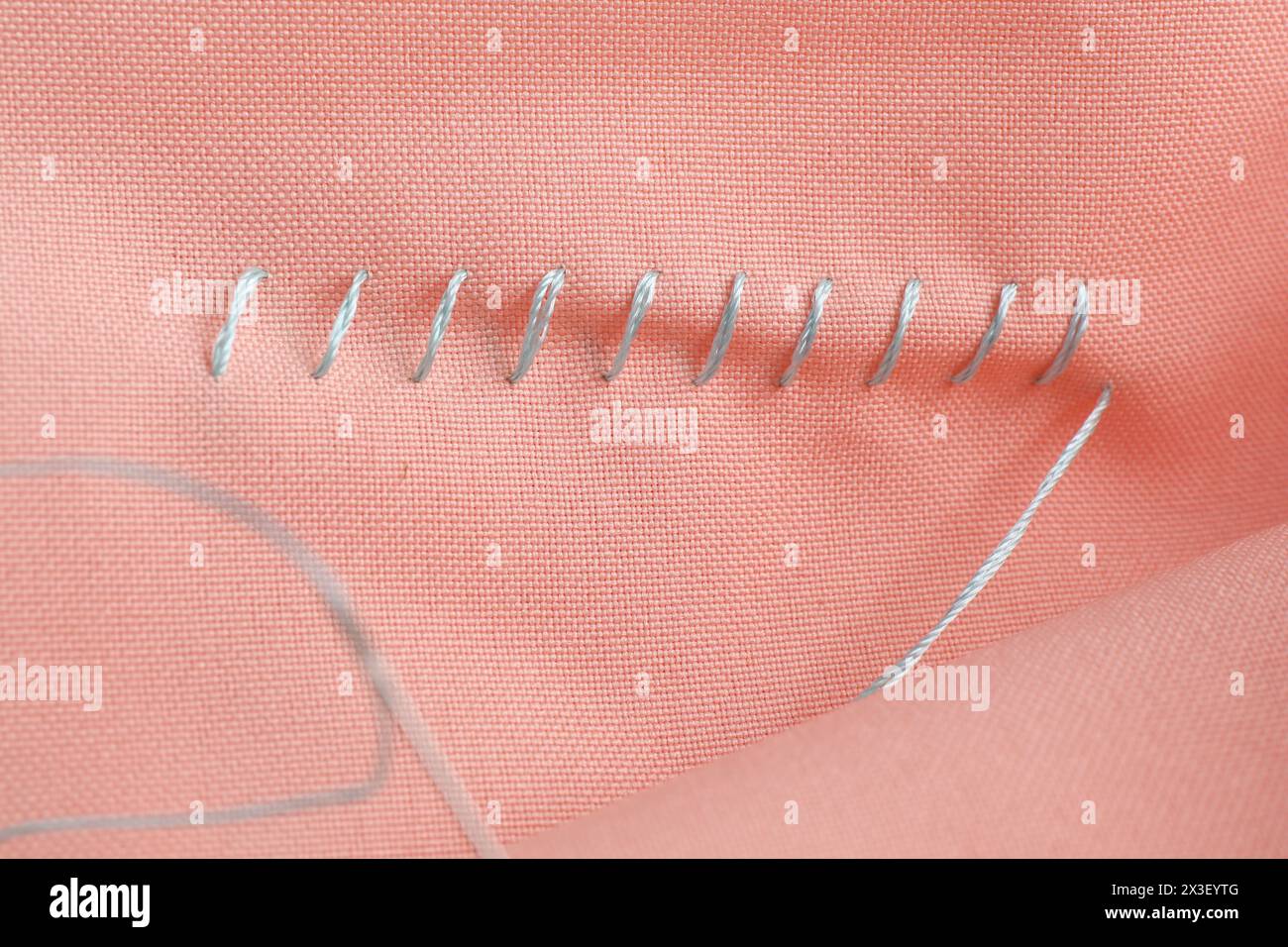 Sewing thread and stitches on coral cloth, top view Stock Photo - Alamy