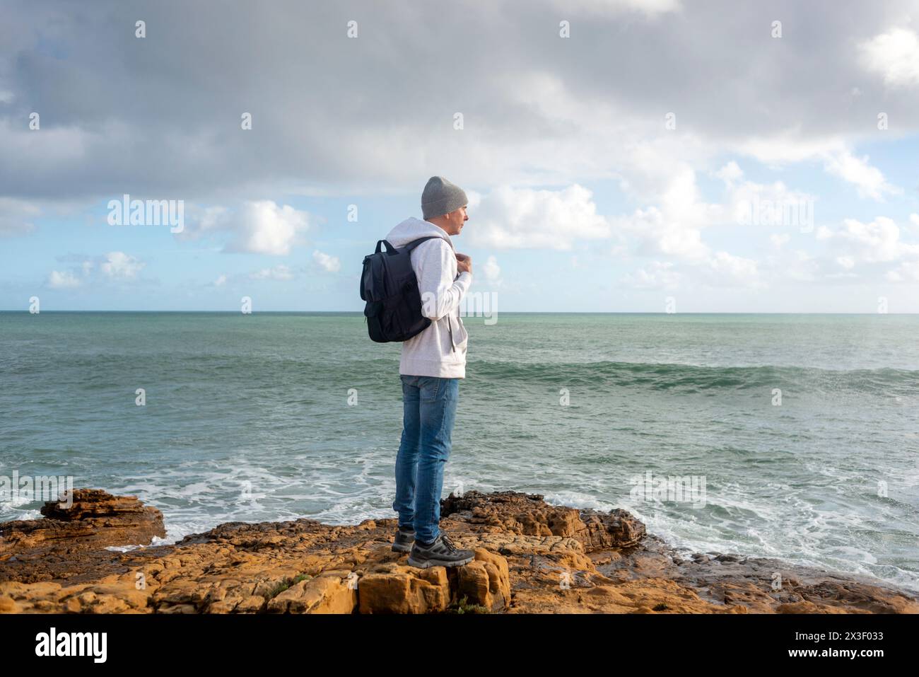 man traveling alone, carrying a backpack, looking into the distance ...