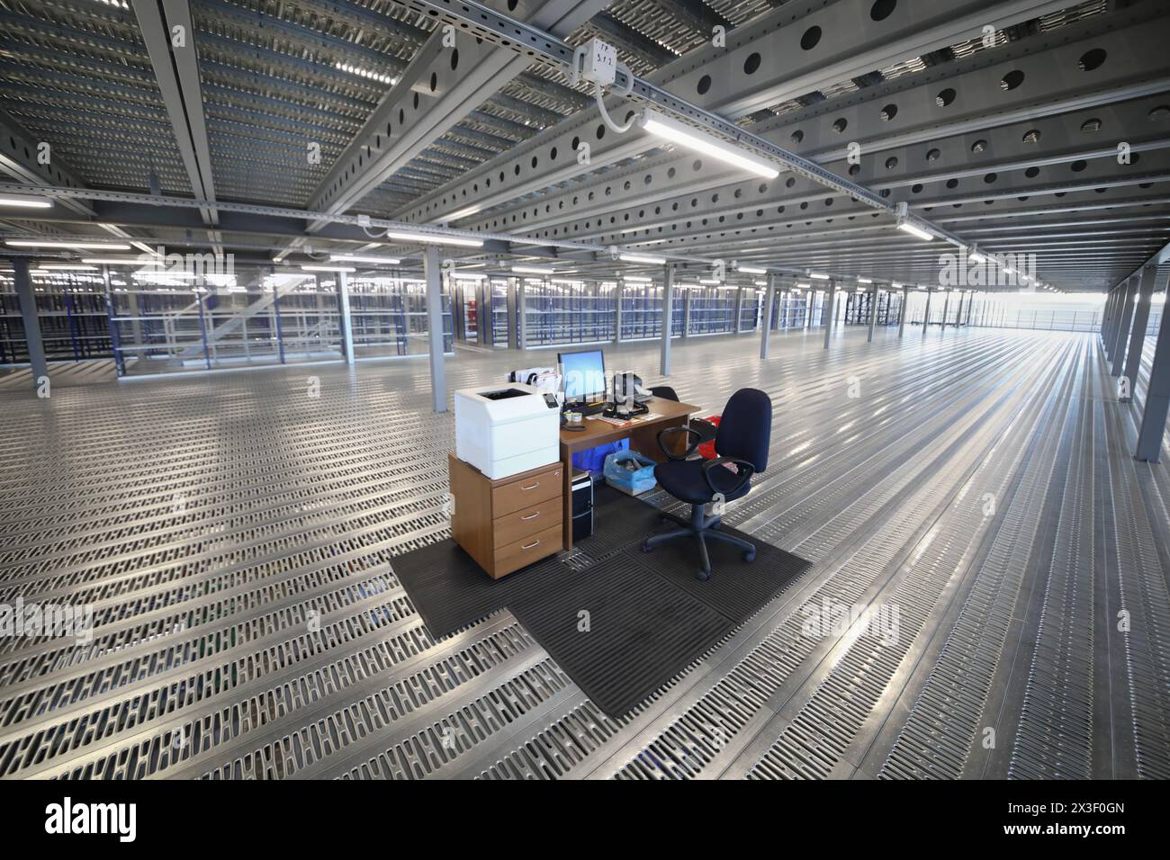 Workplace with computer in warehouse with many shelves - big hall in ...