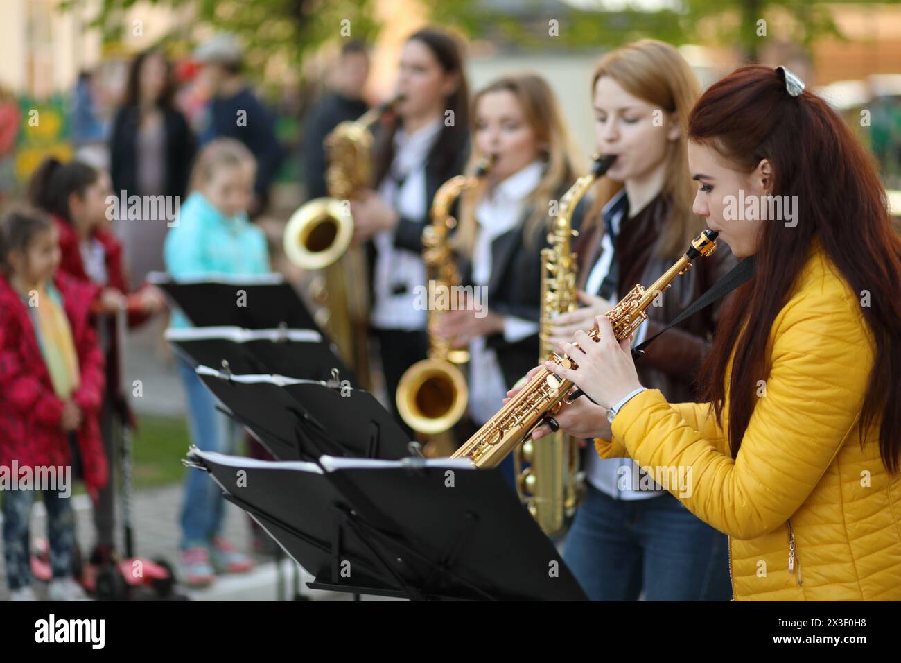Four women play wind instruments outdoor, people listen their, focus on ...