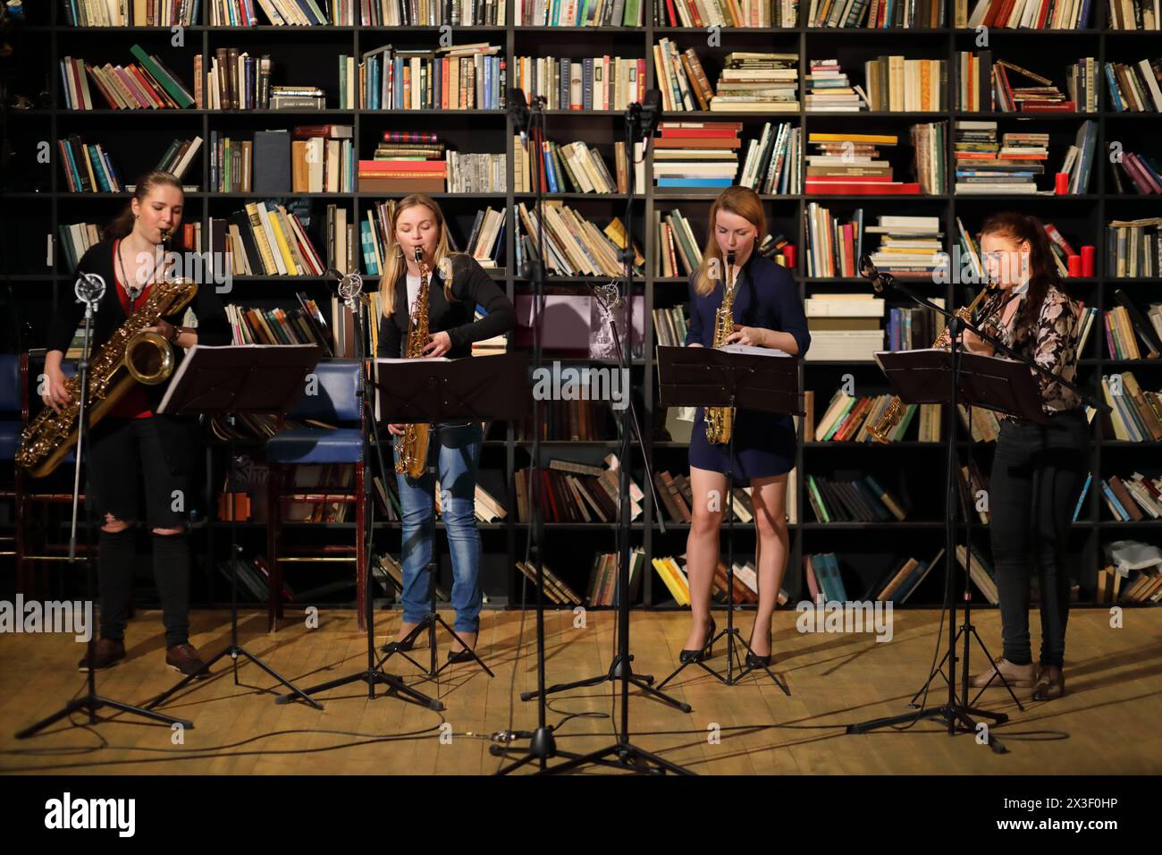 Four young pretty women with wind instruments perform in room with ...