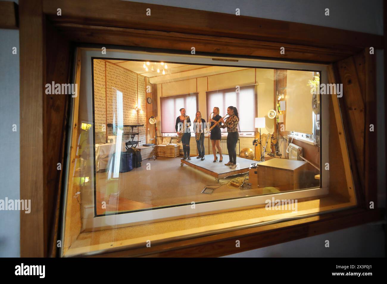Four women play wind instruments in sound recording studio, view from ...