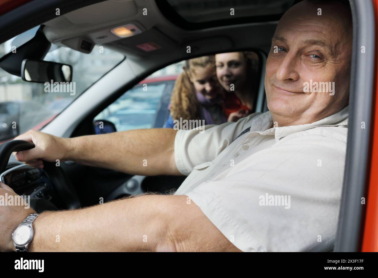 Elderly man fastened sits in car, woman, girl look into window, focus ...