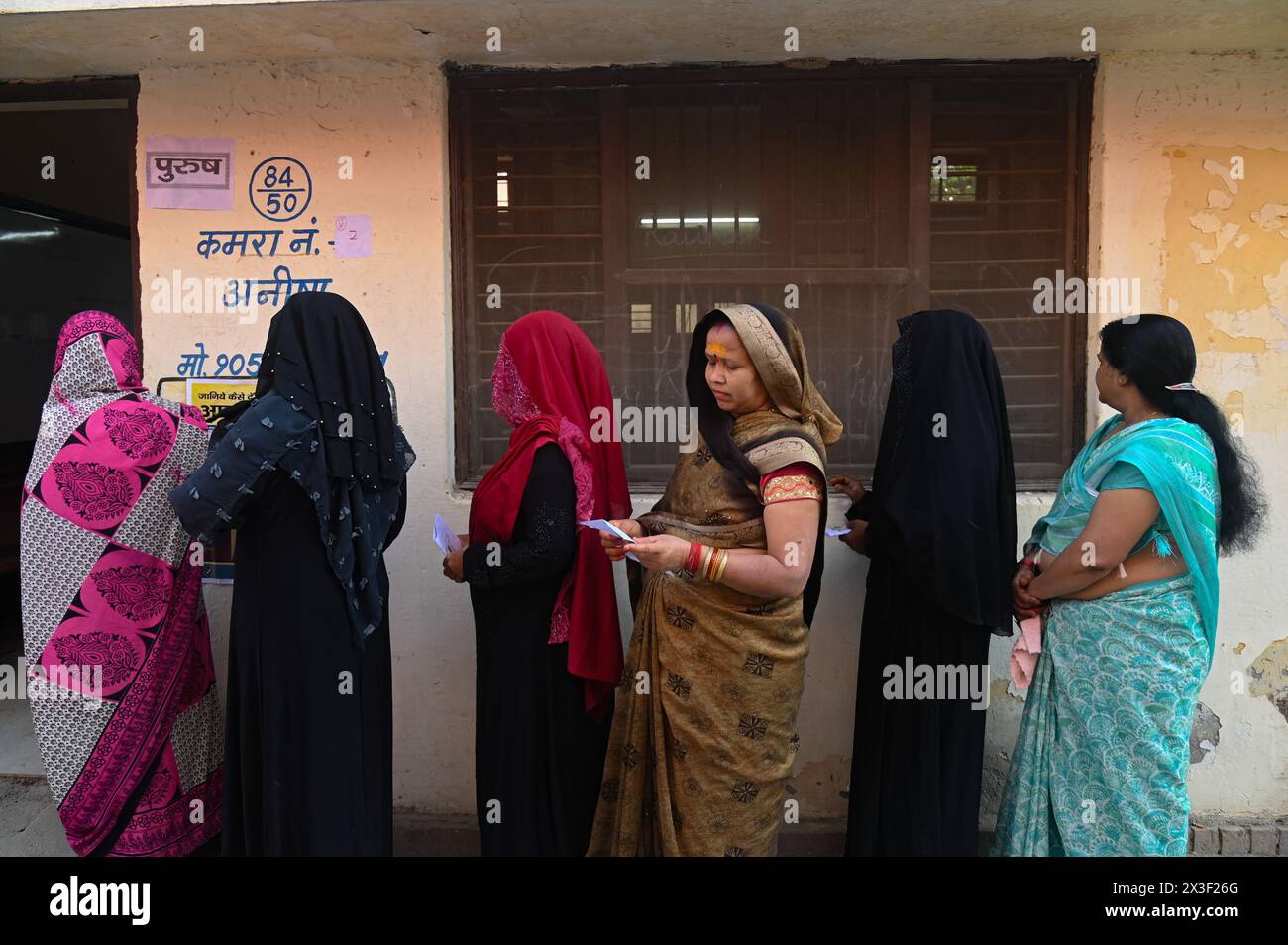 Vrindavan, Uttar Pradesh, India. 26th Apr, 2024. Women stand in a queue ...