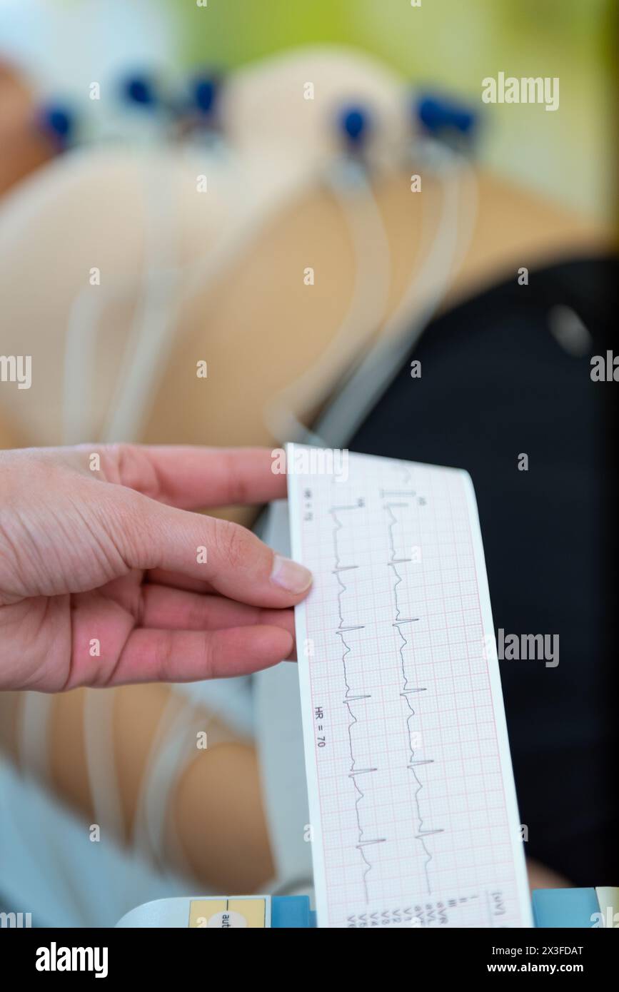 A caregiver is attentively checking a patients vitals with an EKG ...