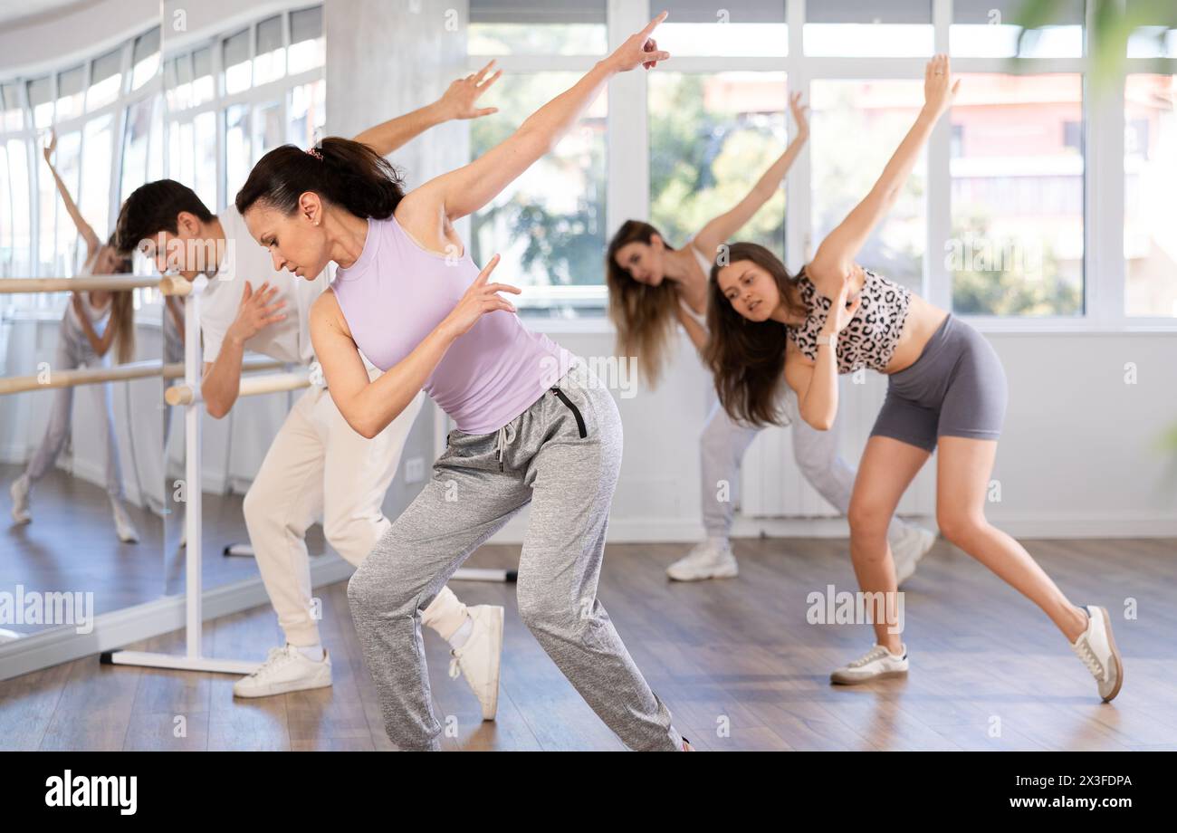 Cheerful young girl and multinational people training synchronous group ...