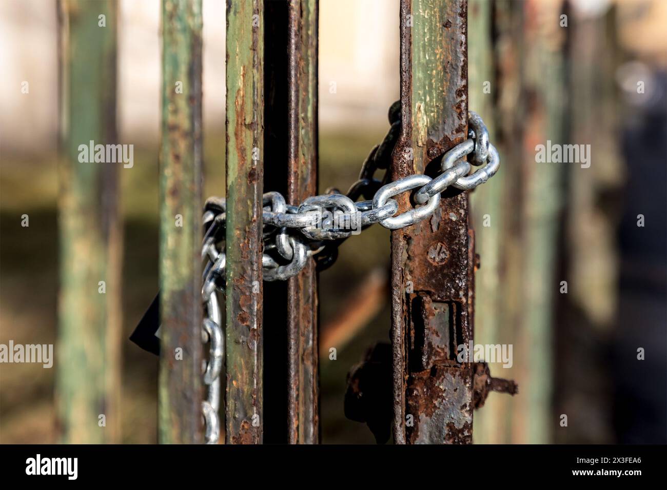 The brand new chain locking the old rusty gate with a focus on a brand ...