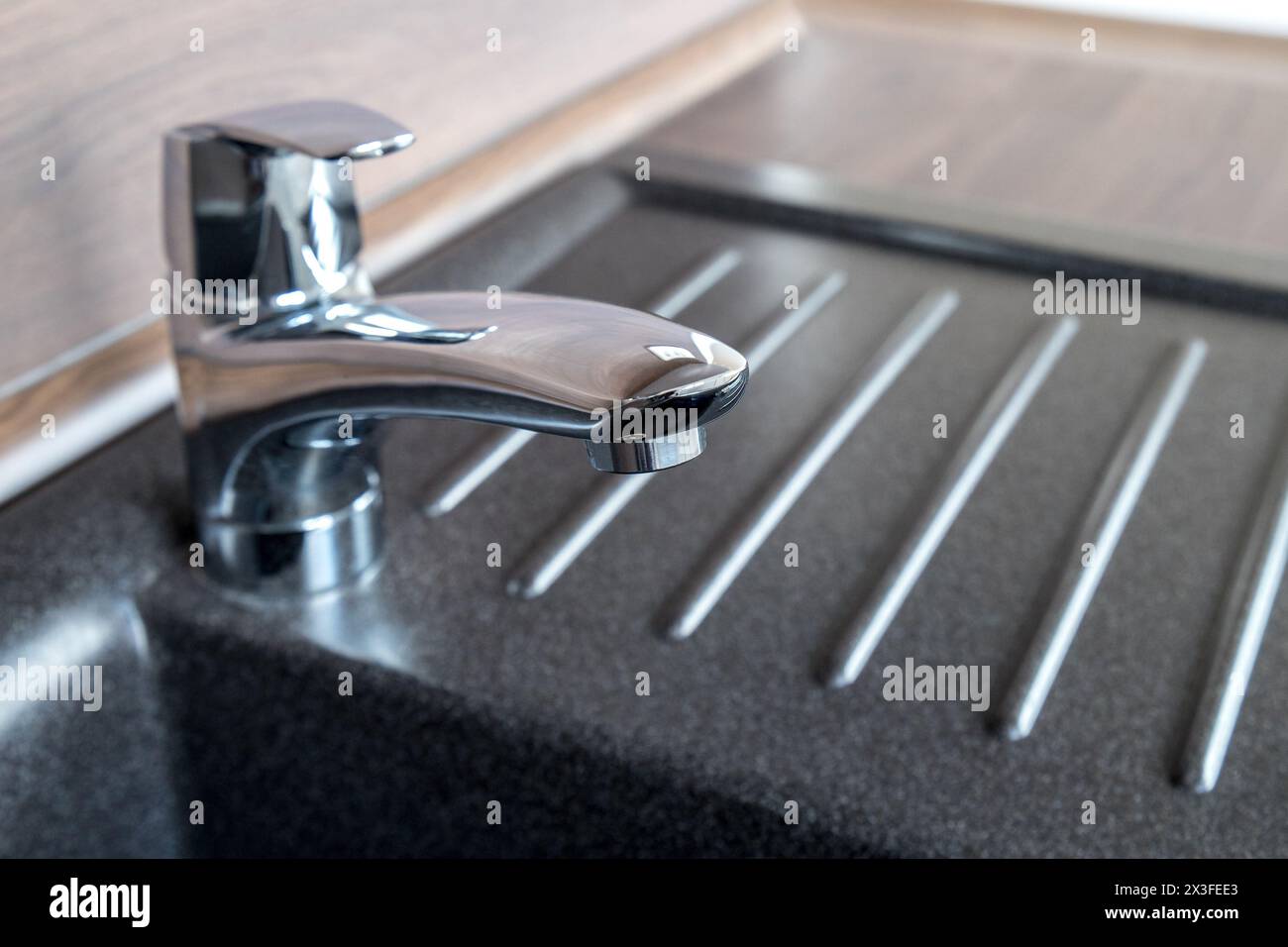 Shiny chrome faucet in a brand new kitchen with a granite sink Stock ...